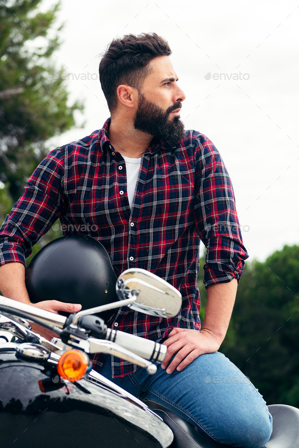 handsome bearded man sitting on his motorcycle Stock Photo by Raul_Mellado