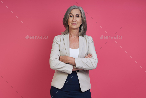 Confident senior woman in formalwear keeping arms crossed while ...
