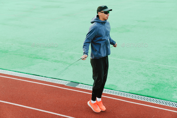Young white runner jumping with rope while working out on stadium Stock ...