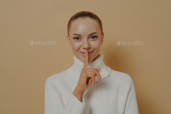 Keep it secret. Young attractive smiling lady saying be quiet with ...