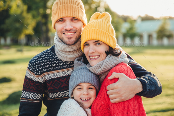Adorable little child stand close to her affectionate parents, enjoy ...