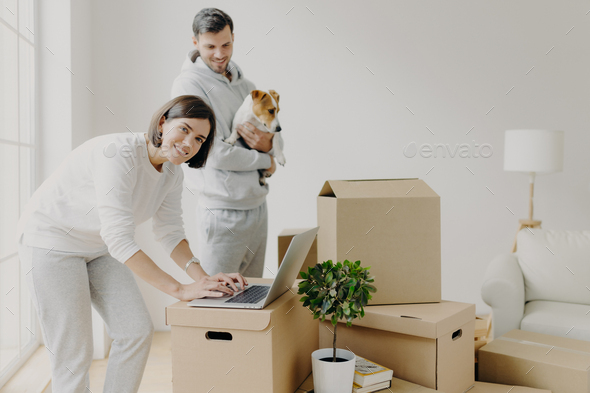 Happy home buyers pose near unpacked boxes, enjoy relocation in new ...