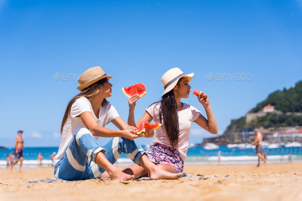 Portrait of two friends in summer on the beach eating a watermelon with ...