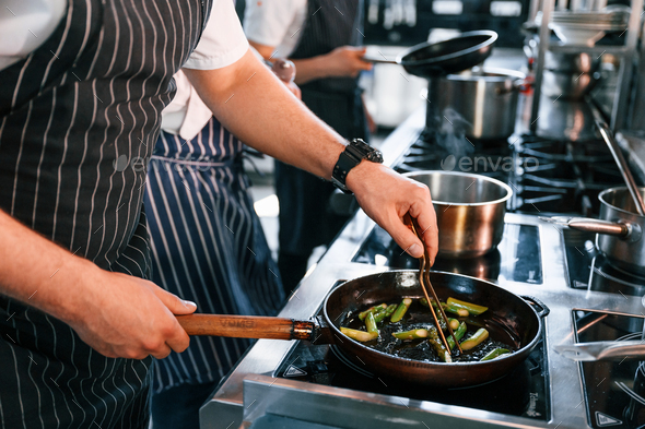 Side view. Kitchen workers is together preparing the food Stock Photo ...