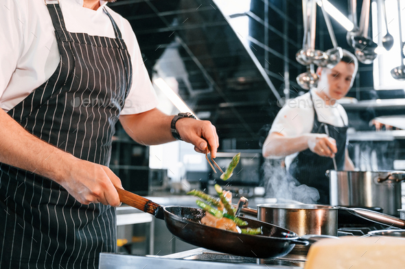 Side view. Kitchen workers is together preparing the food Stock Photo ...