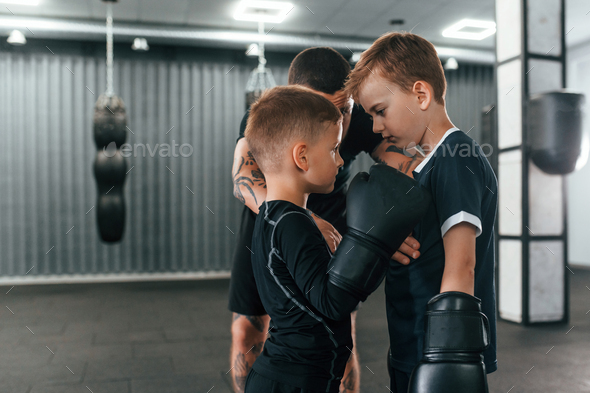 Preparing for the sparring. Young tattooed coach teaching the kids ...