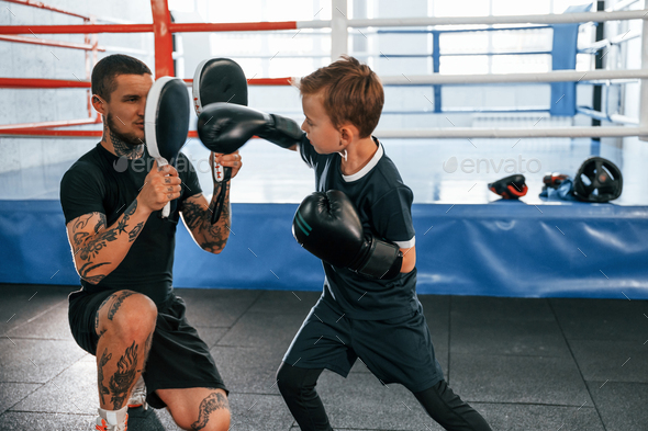 Giving advices. Coach is teaching the boy box techniques indoors Stock ...
