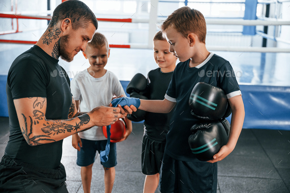 Preparing for the sparring. Young tattooed coach teaching the kids ...