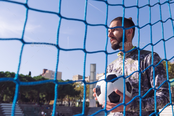 handsome football player through the goal net Stock Photo by Raul_Mellado
