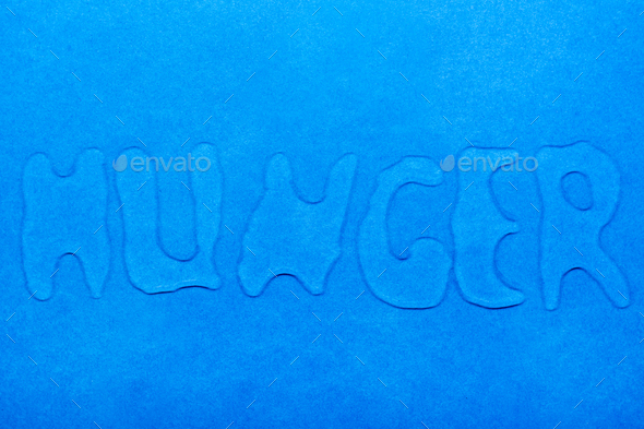 The word "hunger" is written with water droplets on a blue smooth ...