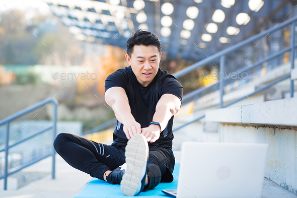 Asian male athlete studies online on the help of a laptop computer ...