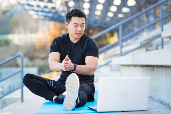 handsome asian fitness coach holds workout classes online using video ...