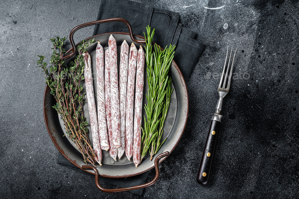 Spanish tapa mini fuet sausage with herbs. Black background. Top view ...
