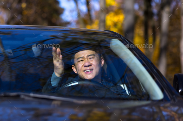 Furious angry asian man standing in a traffic jam beeps and hurries ...