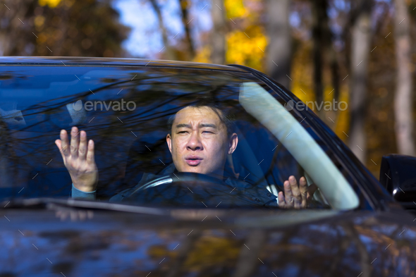 Furious angry asian man standing in a traffic jam beeps and hurries ...