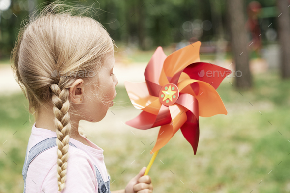 Cute little girl blowing in the windmill in the windmill Stock Photo by ...