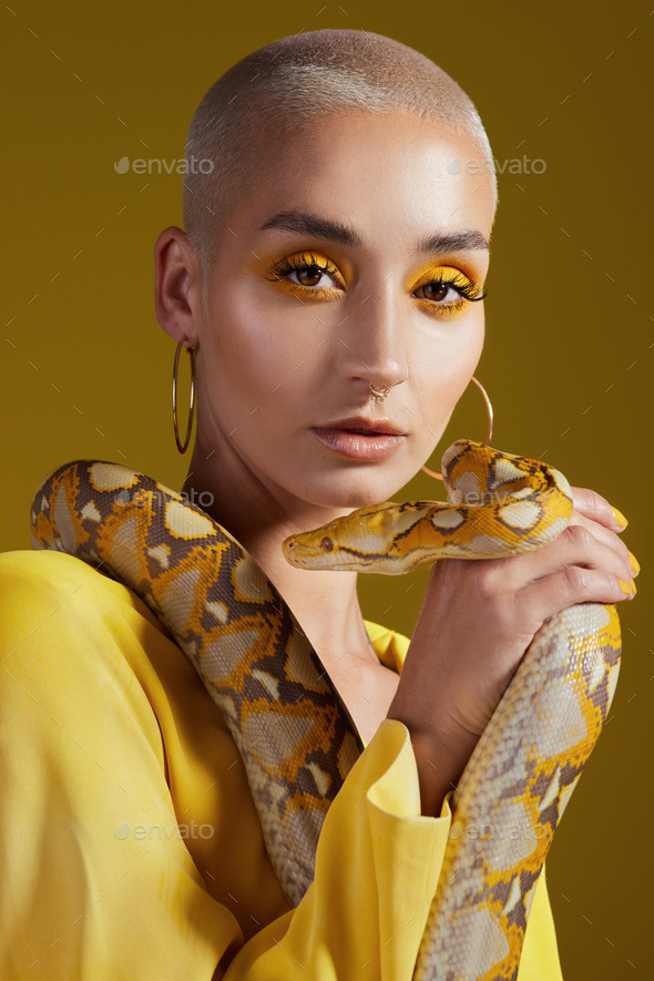 Shot of a fashionable woman holding a snake while modelling a yellow ...
