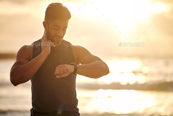 Shot of a sporty young man checking his pulse while exercising outdoors ...