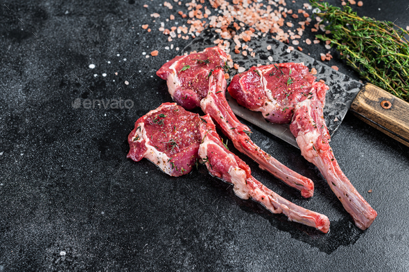Raw uncooked lamb mutton meat chops steaks on a butcher cleaver. Black ...