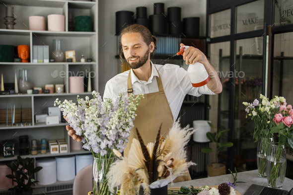 Smiling florist in uniform work in a flower shop behind counter. Stock ...