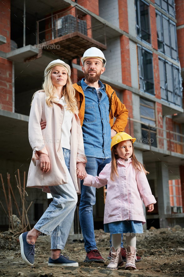 Happy family standing at construction site. Stock Photo by anatoliy_gleb