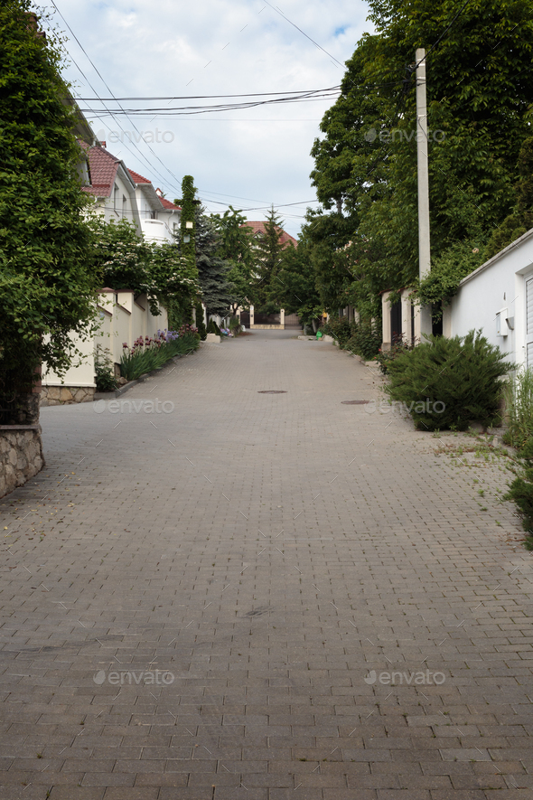 A picturesque alley in a modern suburb. The roadway is paved with ...