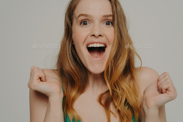 Surprised amazed young woman clenching fits and screaming from ...