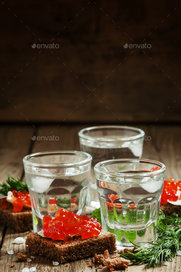 Cold vodka with ice and small snacks sandwiches with butter and red ...