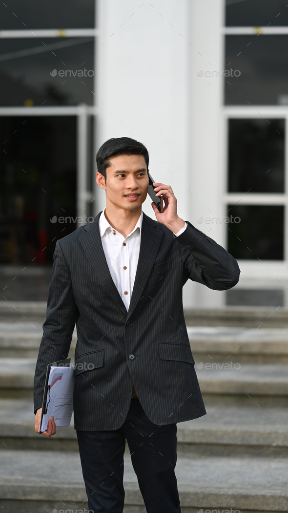 Handsome businessman in black suit standing near modern office building ...