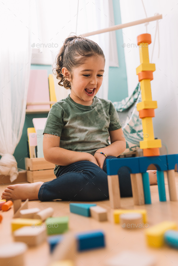 happy girl making constructions with wooden blocks Stock Photo by Raul ...