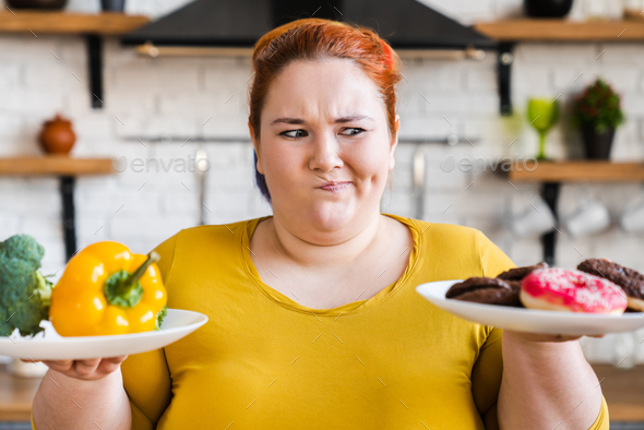 Pensive chubby fat obese caucasian woman choosing between healthy vegan ...