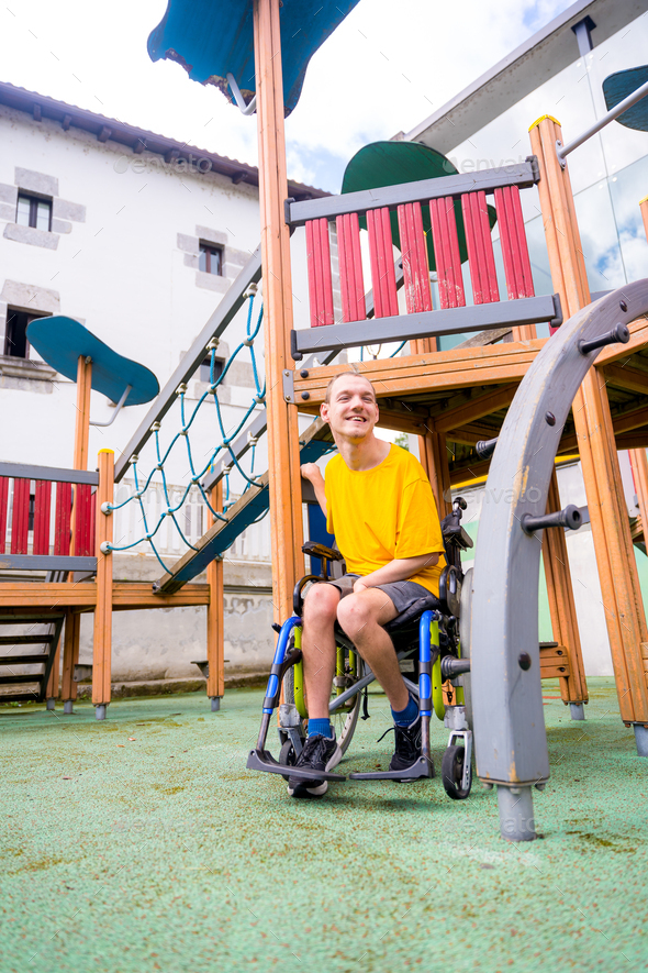 A disabled person in a wheelchair on the swings of a playground having ...