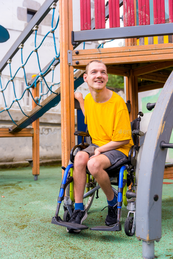 A disabled person in a wheelchair on the swings of a playground having ...