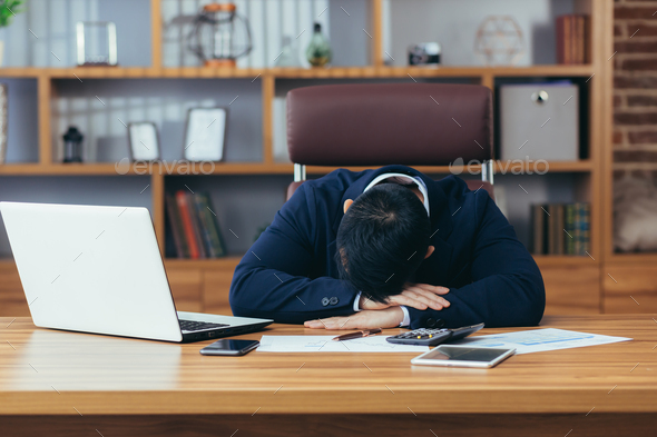 Tired businessman sleeping on the desk, man lying down and resting ...