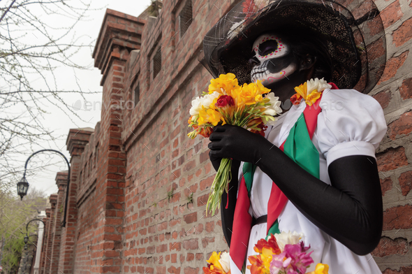 Low angle view of a woman in a costume of Calavera Catrina holding ...