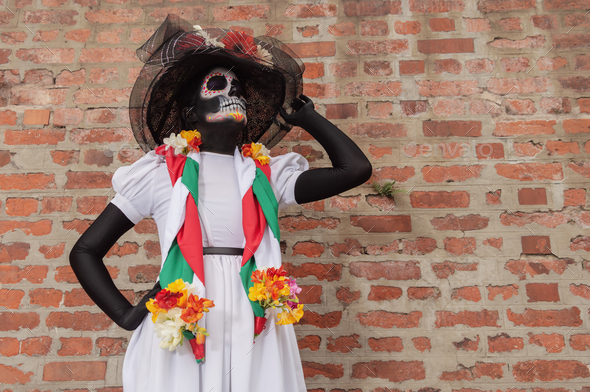 Front view of a woman in a costume of Calavera Catrina holding her ...