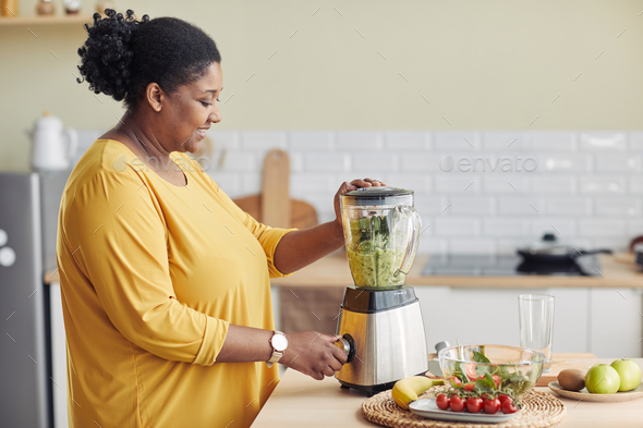 Black Woman Cooking at Home Side View Stock Photo by seventyfourimages