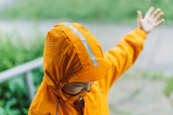 Little boy in yellow suit catches raindrops with his palm Stock Photo ...