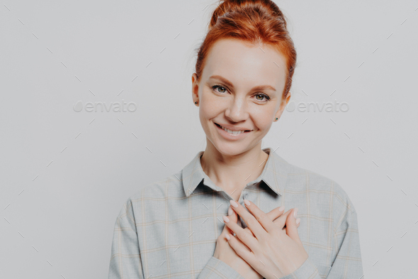 Headshot of young grateful ginger holding hands on chest, feeling love ...
