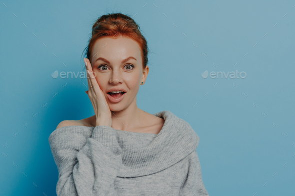Surprised amazed red haired woman with impressed face expression ...