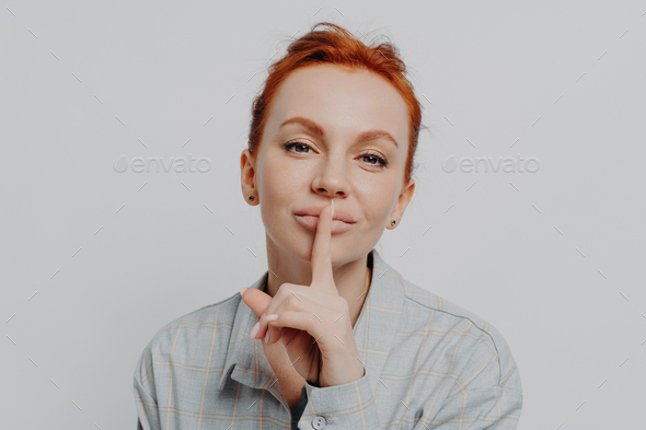 Caucasian female showing shh shush gesture, isolated on grey studio ...