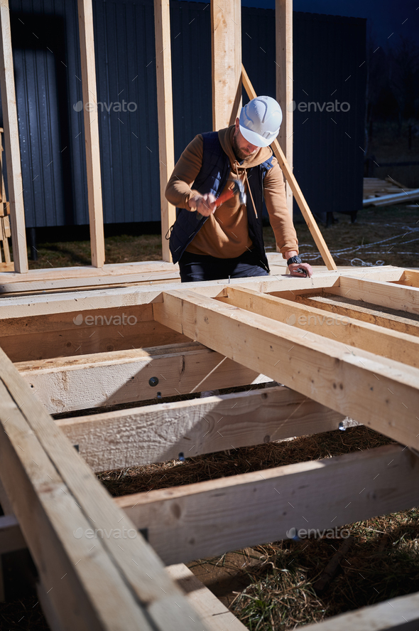 Man worker hammering while building wooden frame house. Stock Photo by ...