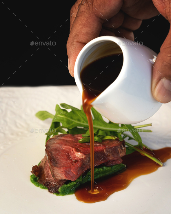 half-cooked lamb meat with arugula and hand pouring gravy Stock Photo ...