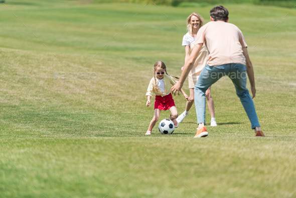 happy family with one child playing with soccer ball in park Stock ...