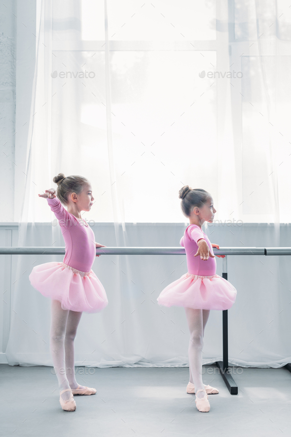 side view of cute small ballet dancers exercising in ballet school ...