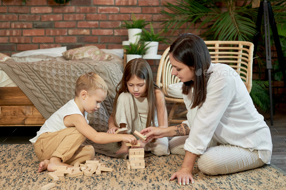 Mom and kids play squirl tower. Woman girl and boy play family puzzle ...