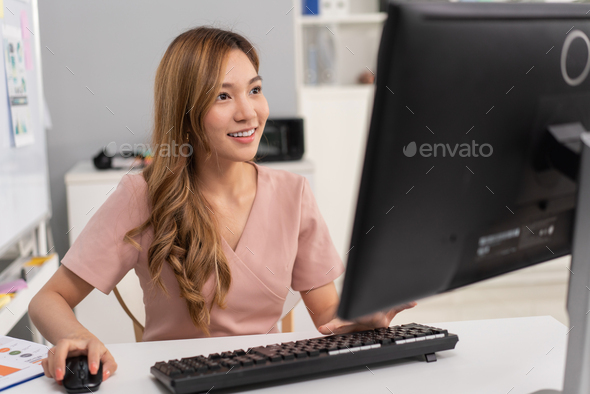 Asian female employee typing on computer keyboard and using mouse Stock ...