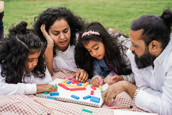 Happy indian family having fun playing with children outdoor at city ...