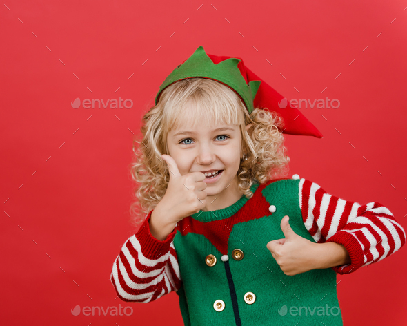 Little girl in Santa elf helper costume on bright red vivid color ...