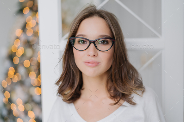 Headshot of lovely young female model in transparent glasses, has dark ...